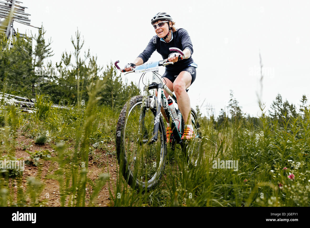 female athlete cyclist rides on trail green grass during Regional ...