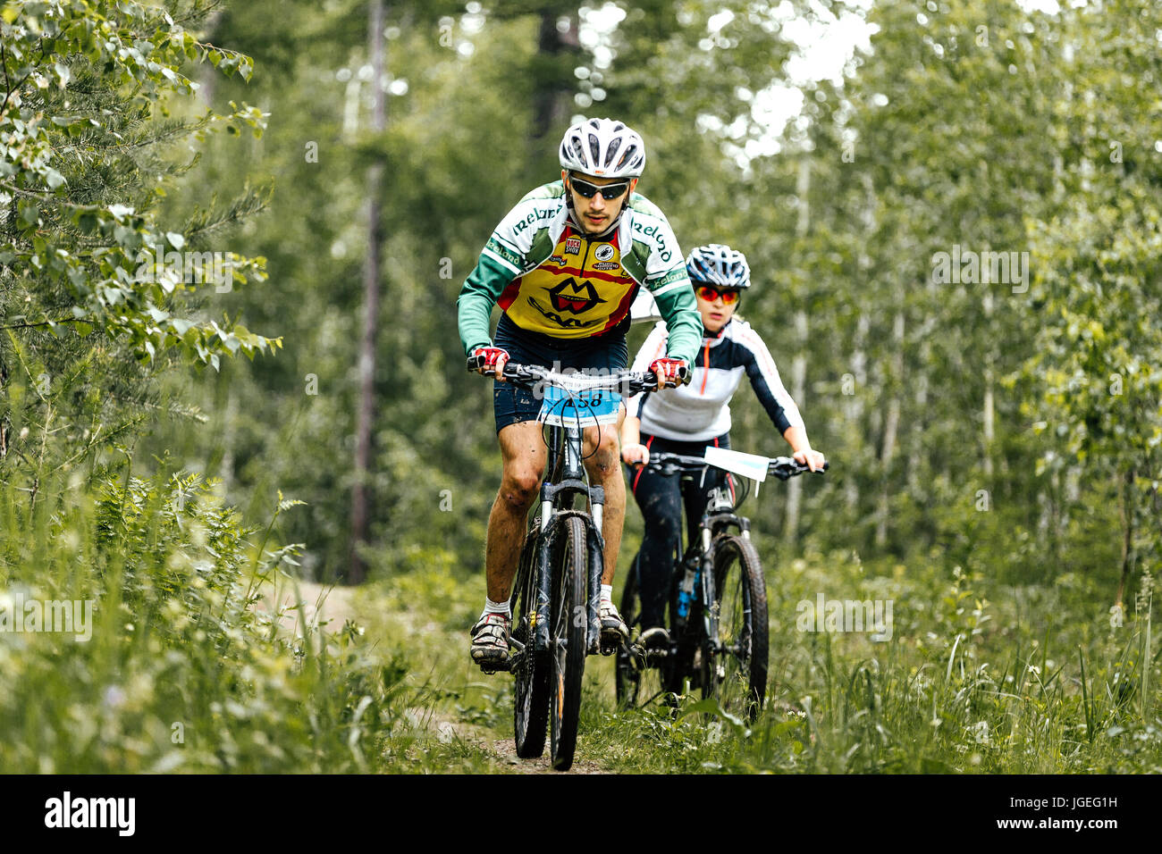 male and female athletes cyclists race in forest during Regional ...