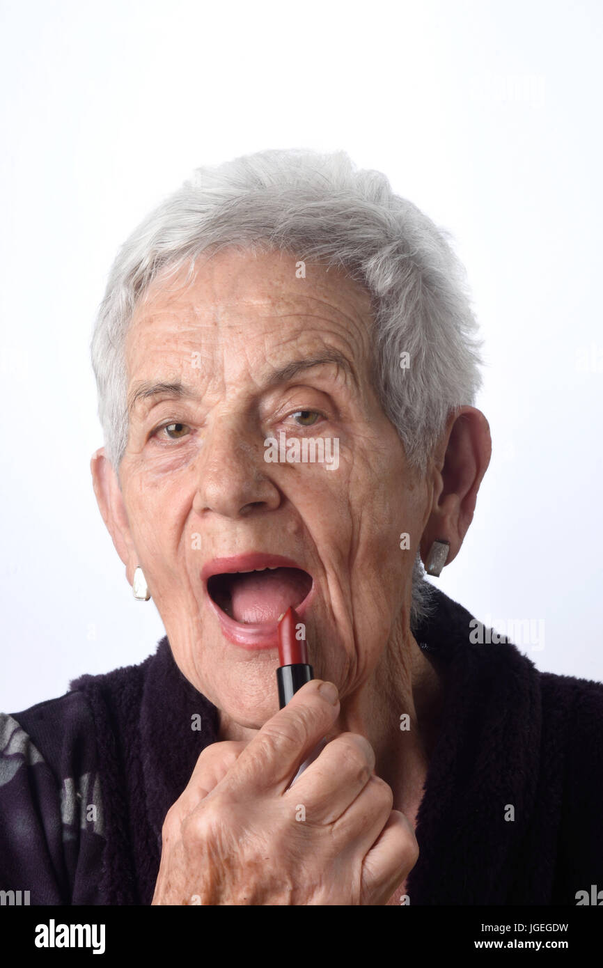 Old woman painting her lips on white background Stock Photo - Alamy