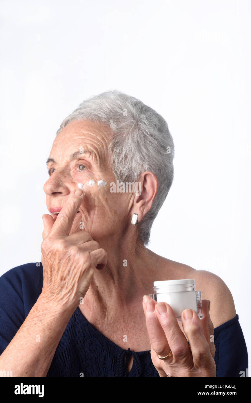 Senior woman applying skin cream or moisturiser to her face Stock Photo ...