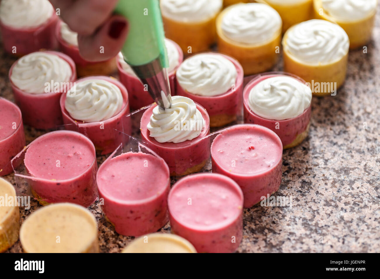 Woman hand decorating mini cakes with pastry cream Stock Photo - Alamy