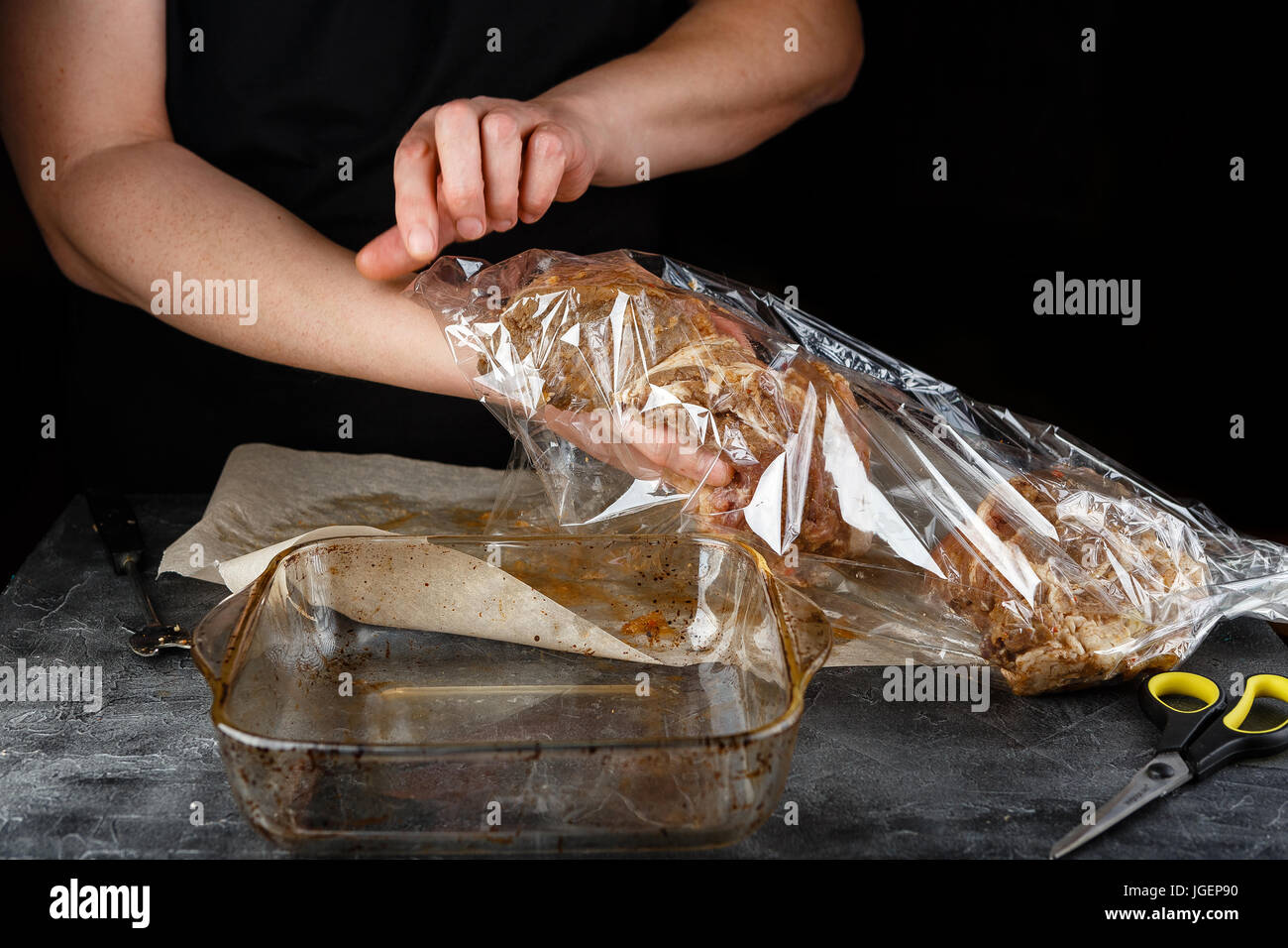 Man packs marinated pieces of meat of pork shoulder in roasting sleeve ...