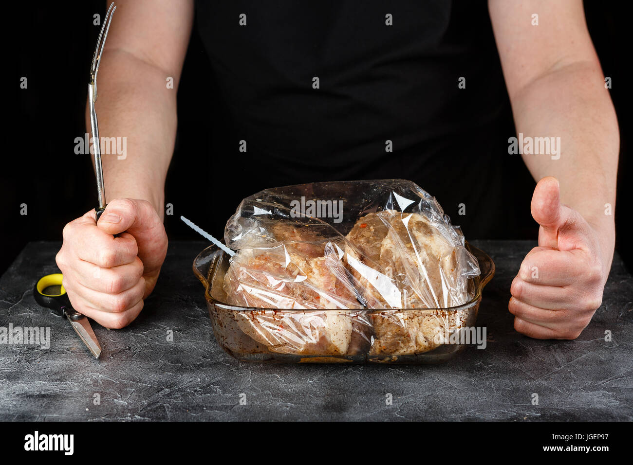 Man stacks marinated meat pieces pork shoulder in the roasting sleeve ...