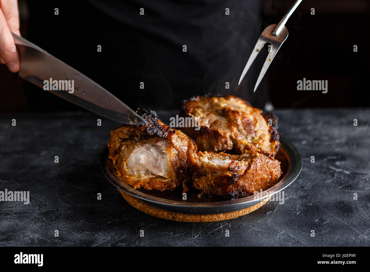 Roasted pieces of pork shoulder blade in metal plate on dark background ...