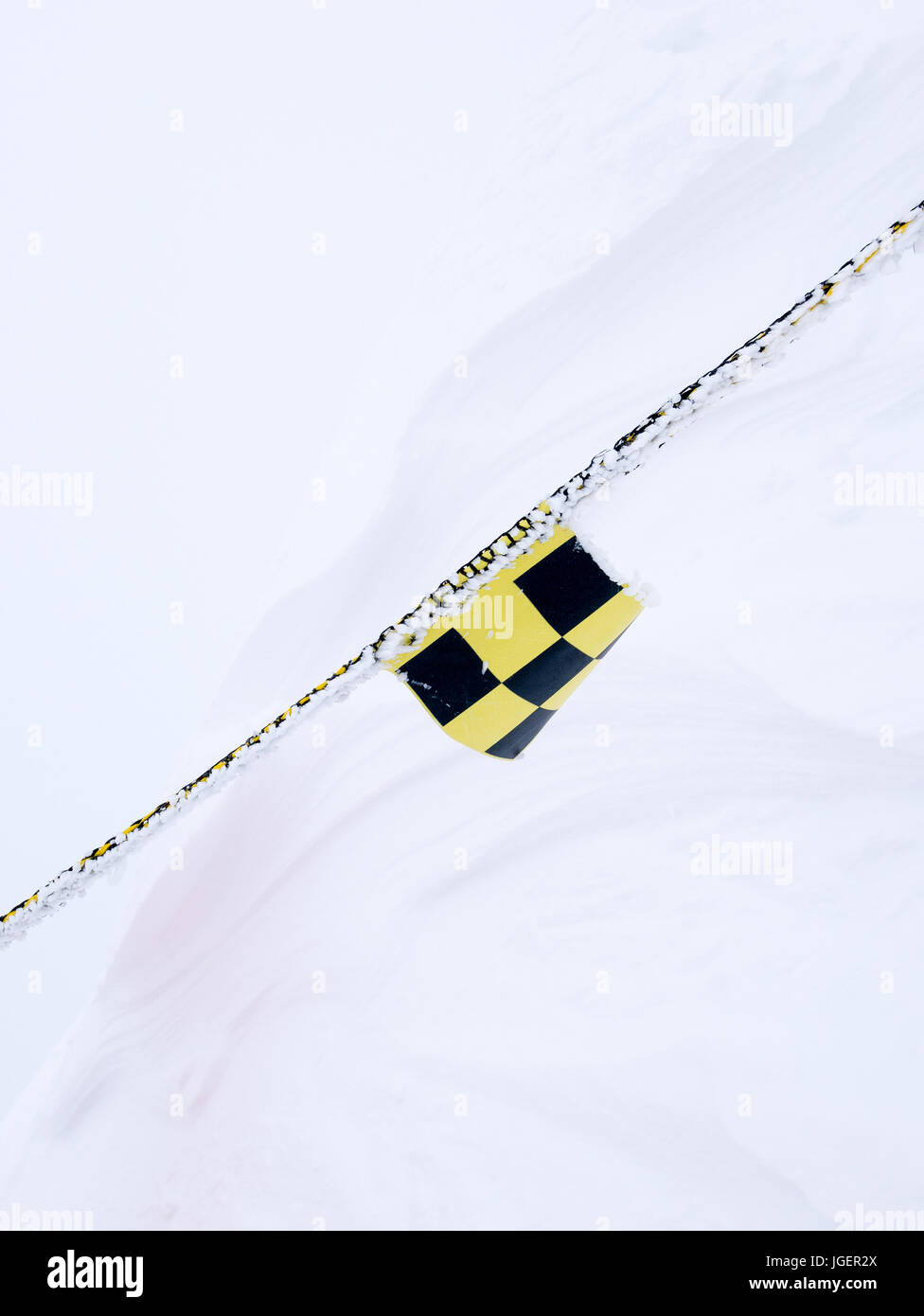 Small avalanche flag hanged on rope at snow background. Warning symbol ...