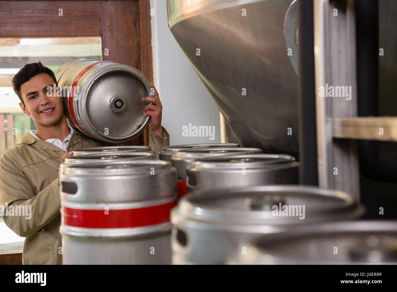 Portrait of smiling male worker carrying keg at warehouse Stock Photo ...