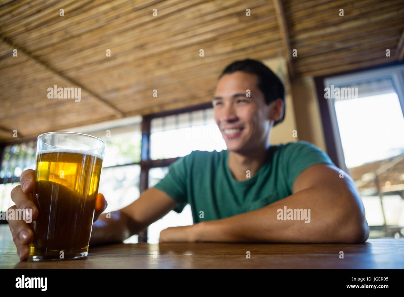Smiling man with beer glass looking away at bar counter Stock Photo - Alamy