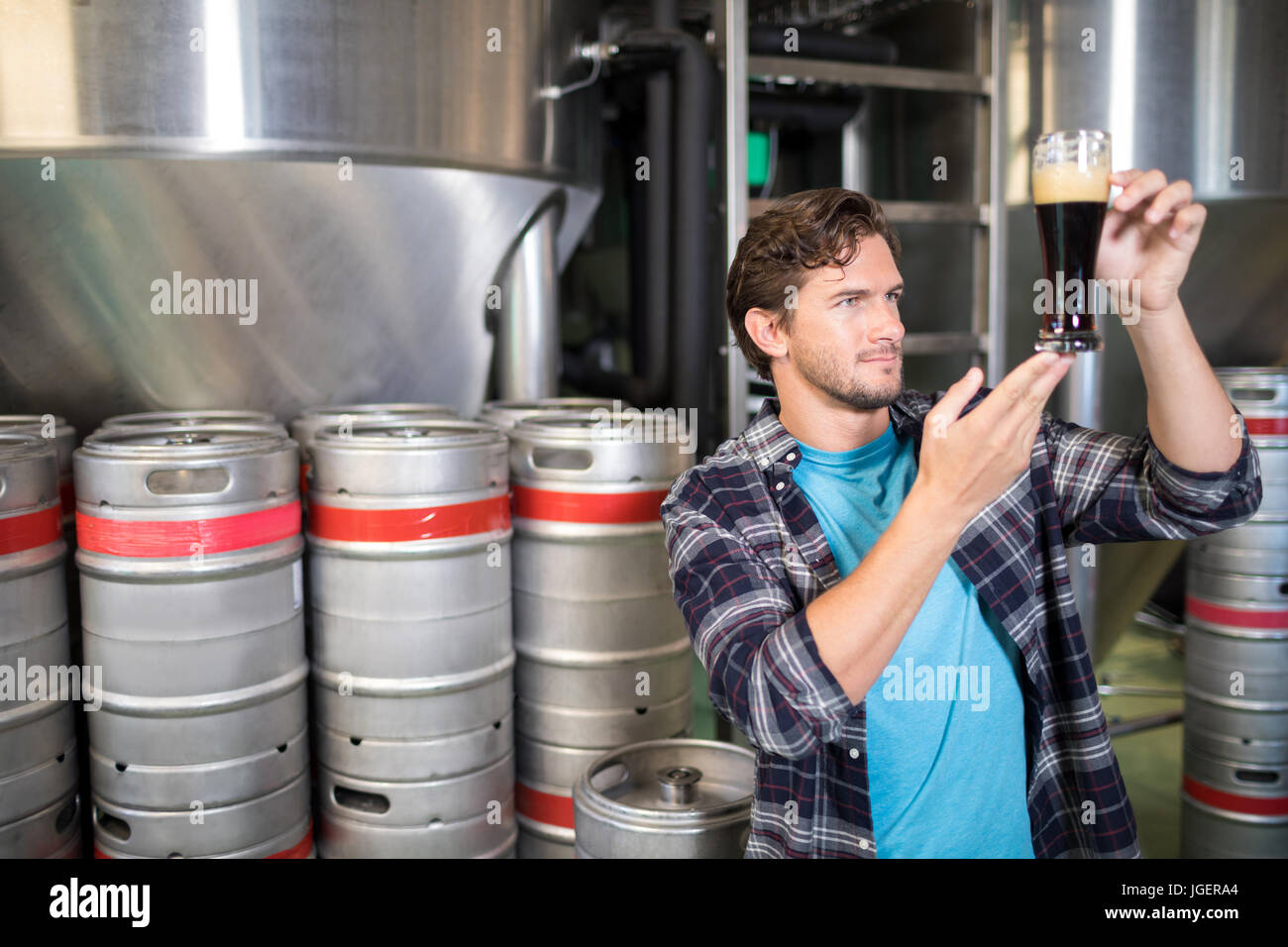 Worker examining beer in glass at warehouse Stock Photo - Alamy