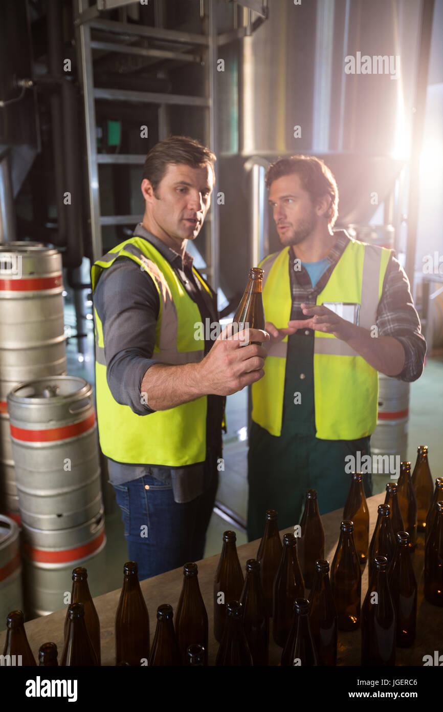 Coworkers examining beer bottles at warehouse Stock Photo - Alamy