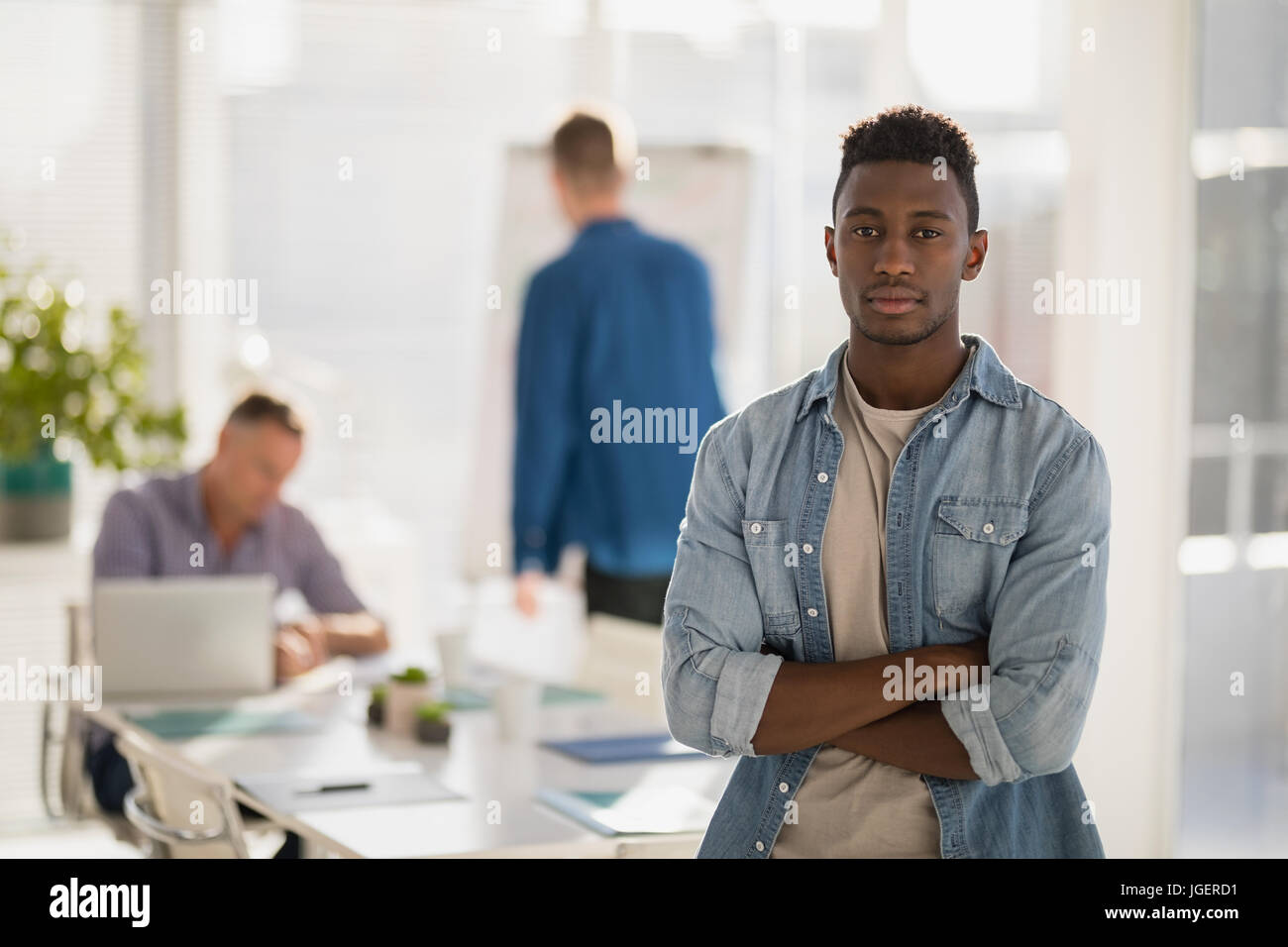 Young male executive standing with arms crossed in the office Stock ...