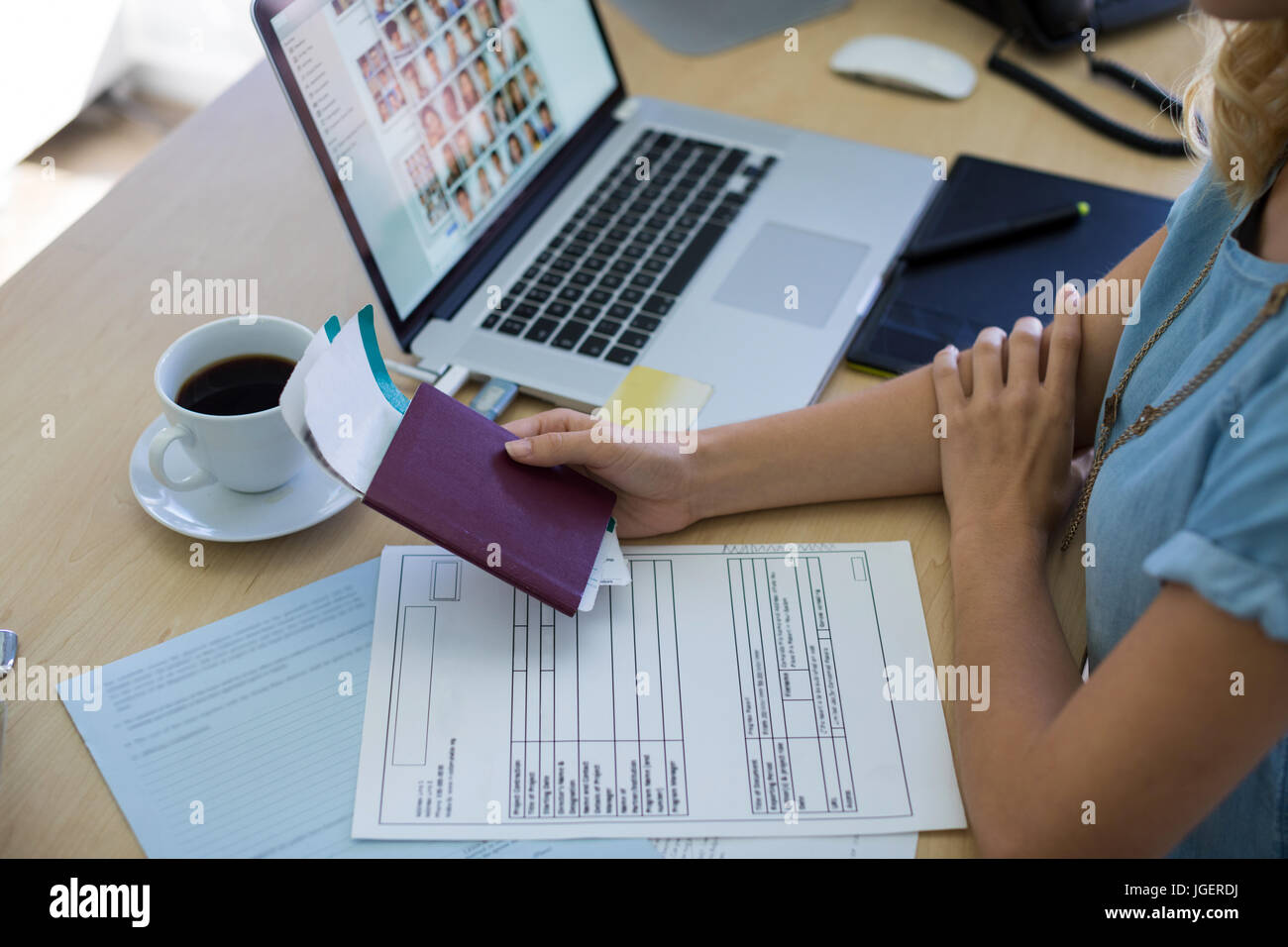 Close-up of female executive holding tickets and passport at her desk ...
