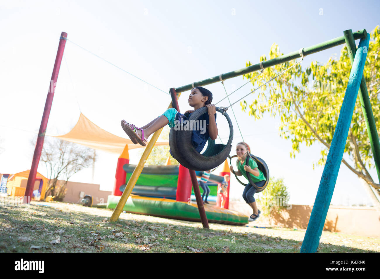 Low angle view of girls swinging at playground against sky Stock Photo ...
