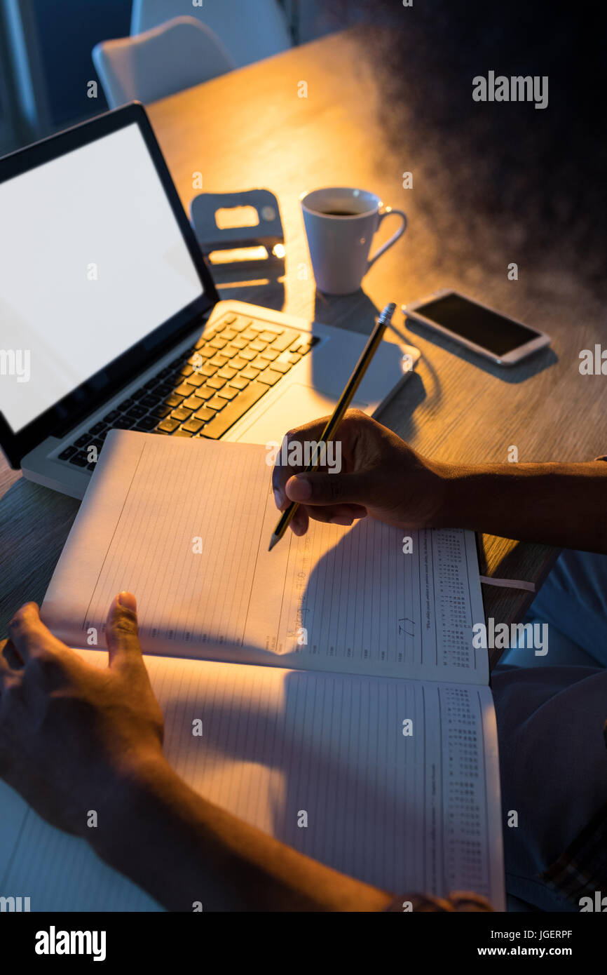 Male executive writing in diary at his desk in office Stock Photo - Alamy
