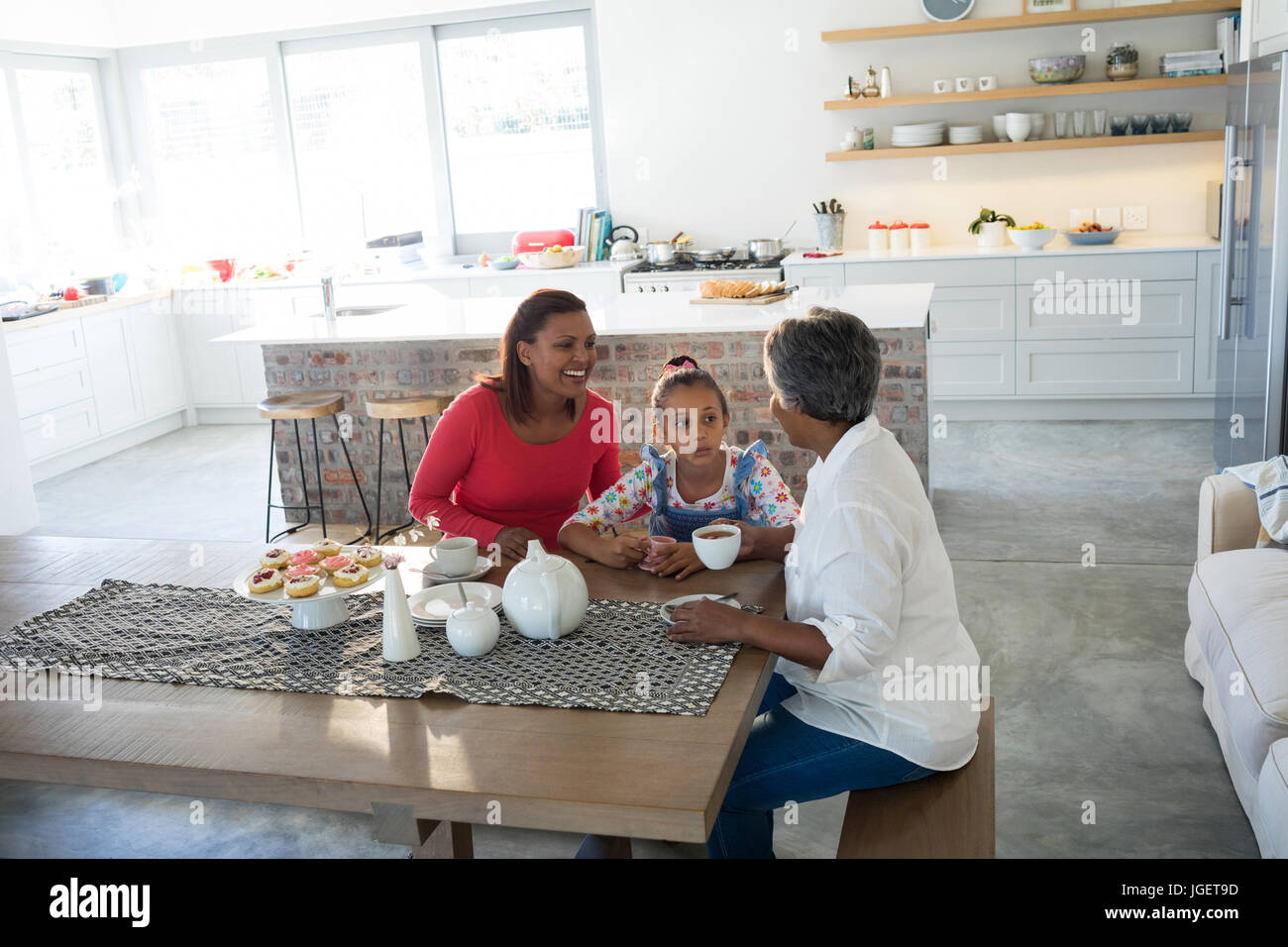 Portrait of happy multi-generation family having tea in dining table at ...