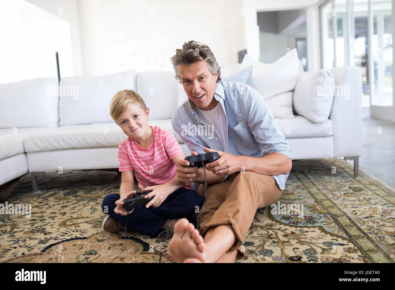 Father and son playing video game in living room at home Stock Photo ...