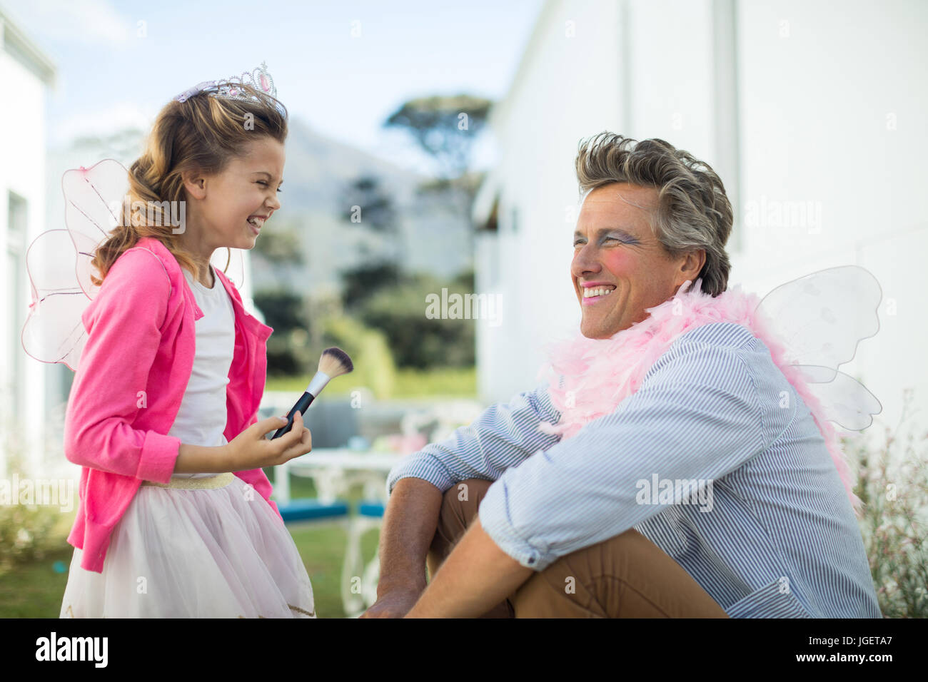 Smiling daughter and father in fairy costume having fun at garden Stock ...