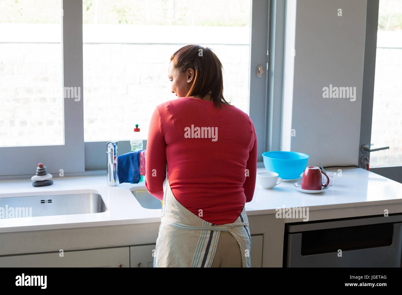 Rear view of woman washing utensil in kitchen sink Stock Photo - Alamy