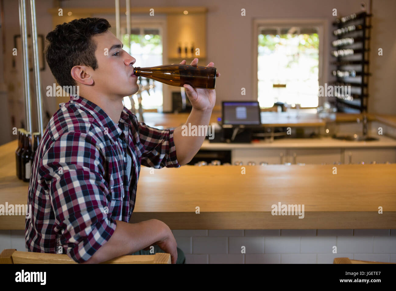Young man drinking beer at counter in restaurant Stock Photo - Alamy