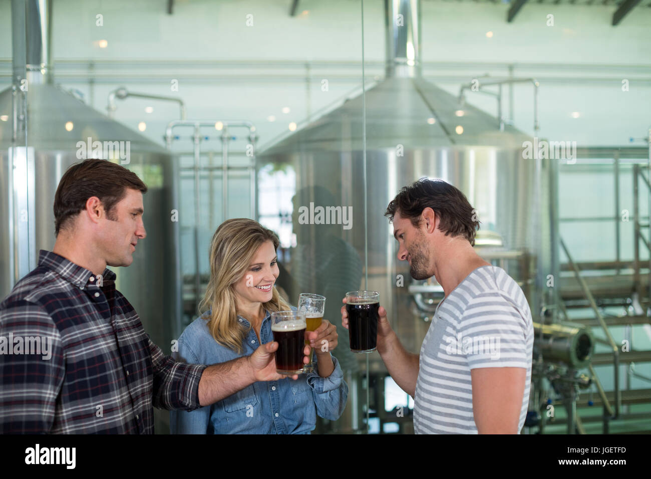 Smiling friends tasting beer at factory Stock Photo - Alamy