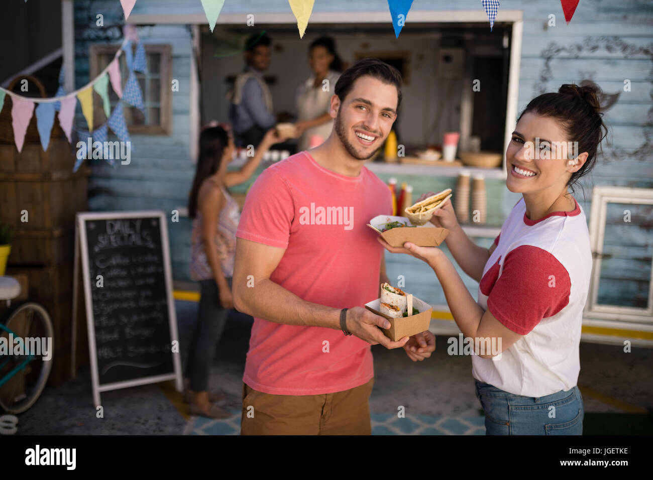 Portrait of smiling couple standing with snacks Stock Photo - Alamy