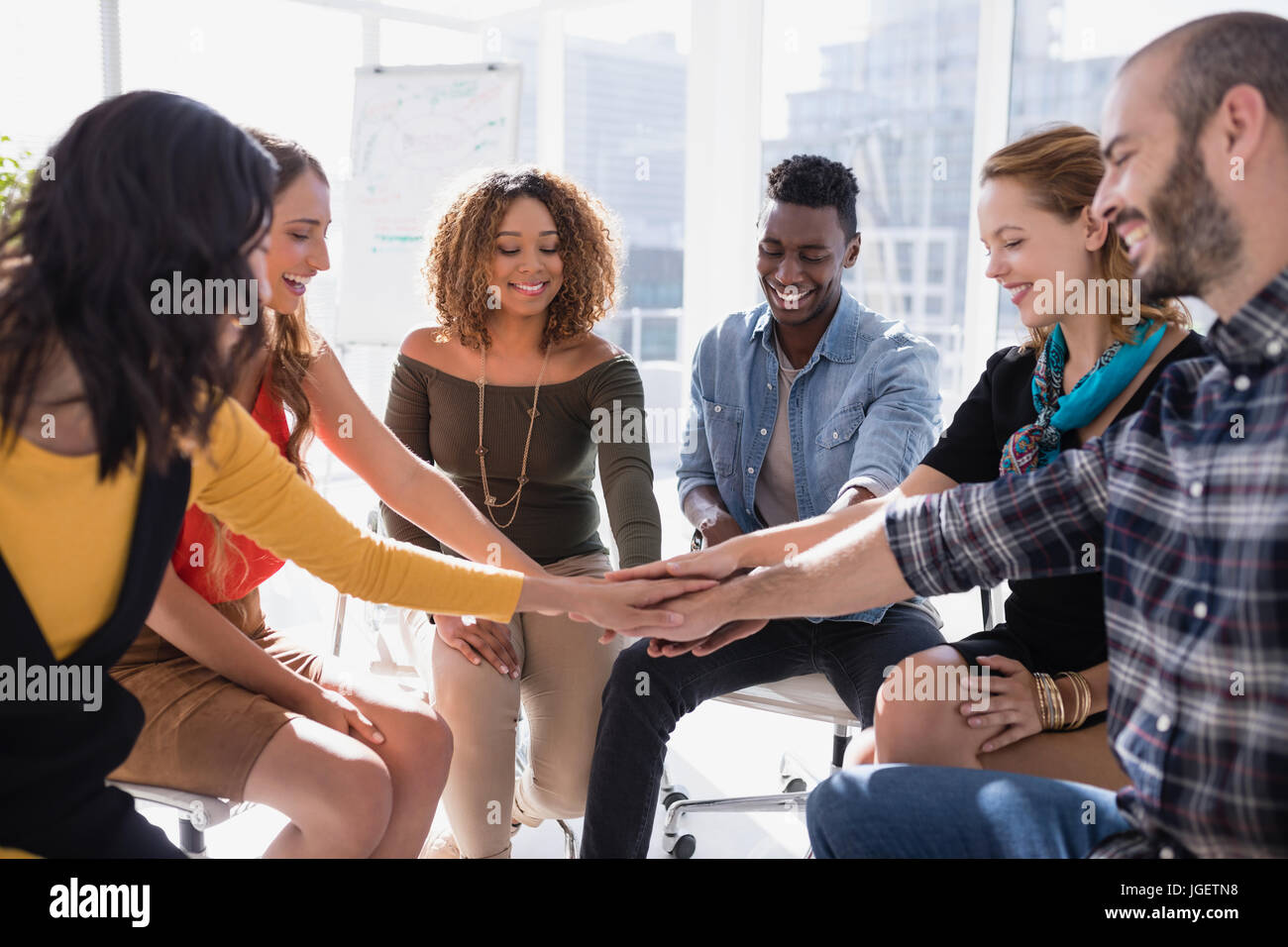 Group of happy colleagues forming hand stack in office Stock Photo - Alamy