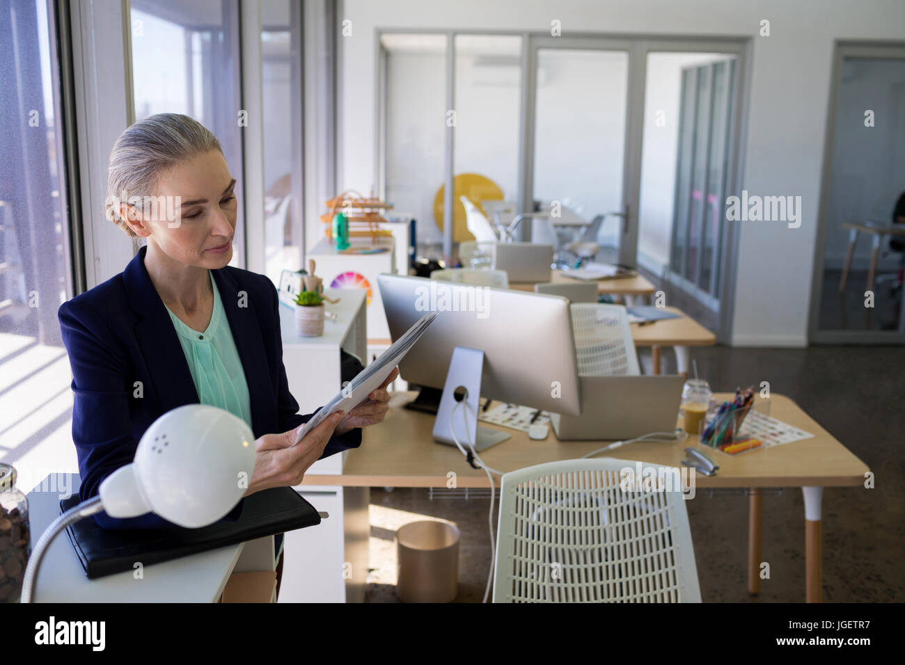 Female executive reading document at her desk in office Stock Photo - Alamy