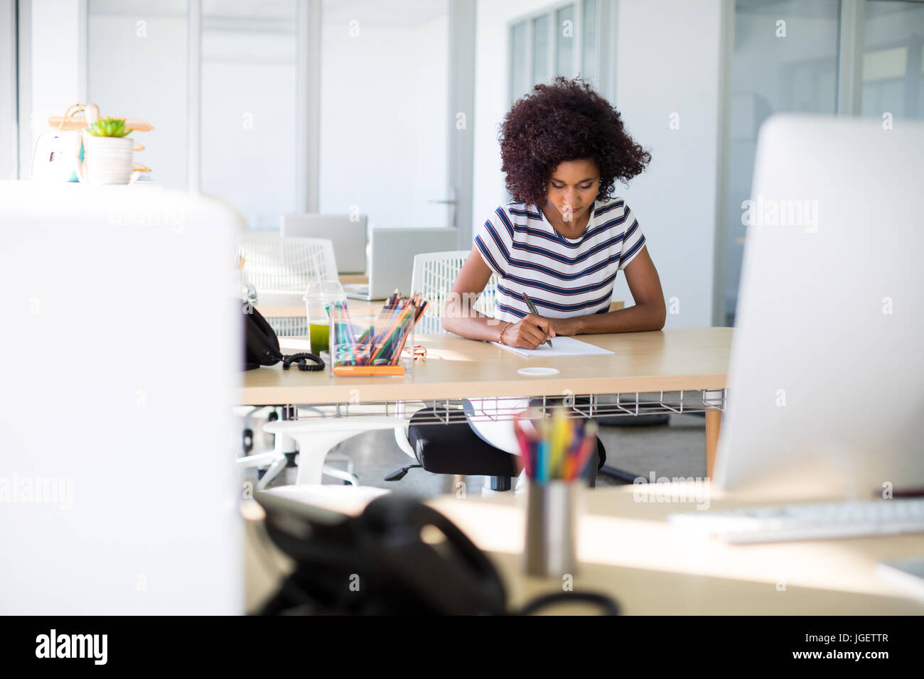 Female executive writing on paper at her desk in office Stock Photo - Alamy