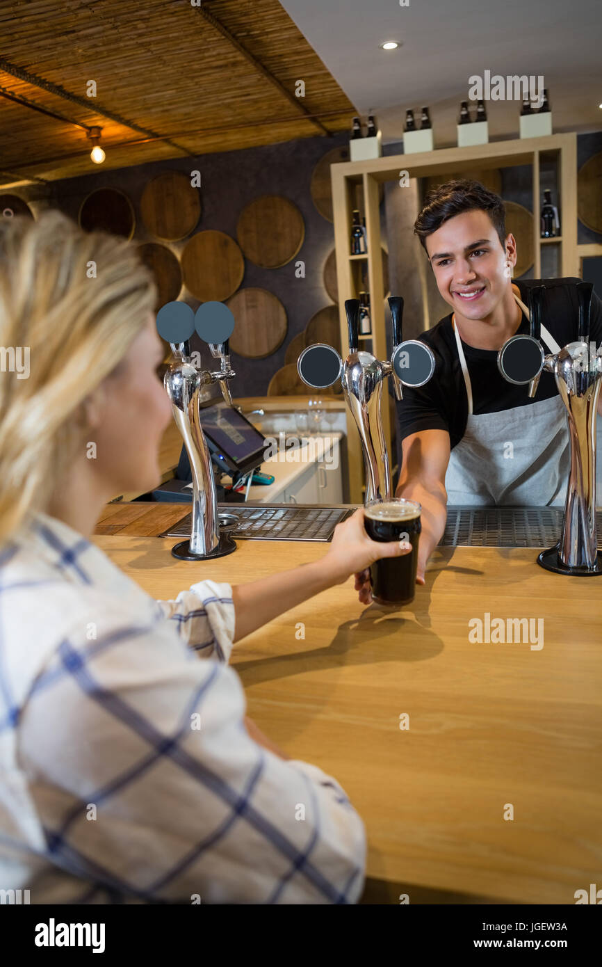 Smiling bartender serving drink to woman at counter in restaurant Stock ...