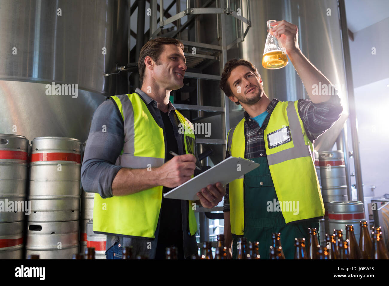 Coworkers examining beer in beaker at warehouse Stock Photo - Alamy