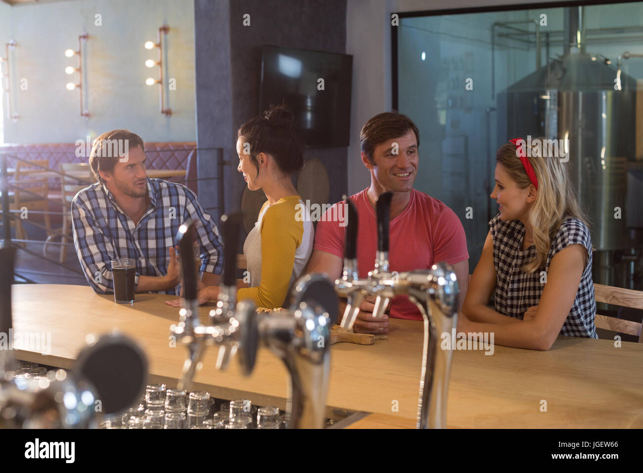 Friends talking while standing at bar counter Stock Photo - Alamy