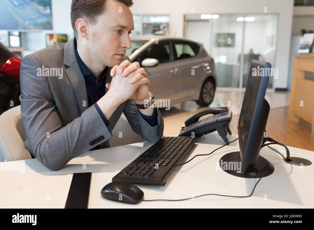 Salesman using computer while working in car showroom Stock Photo - Alamy