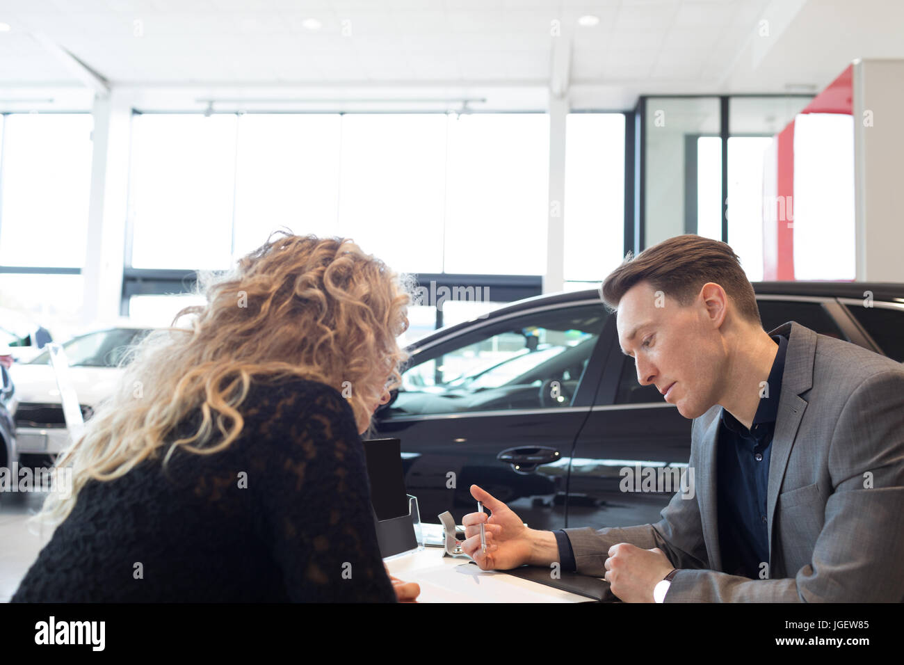 Salesman discussing over document with customer in showroom Stock Photo ...