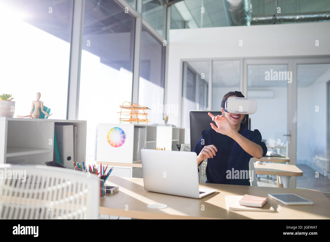 Female executive using virtual reality headset at her desk in office ...
