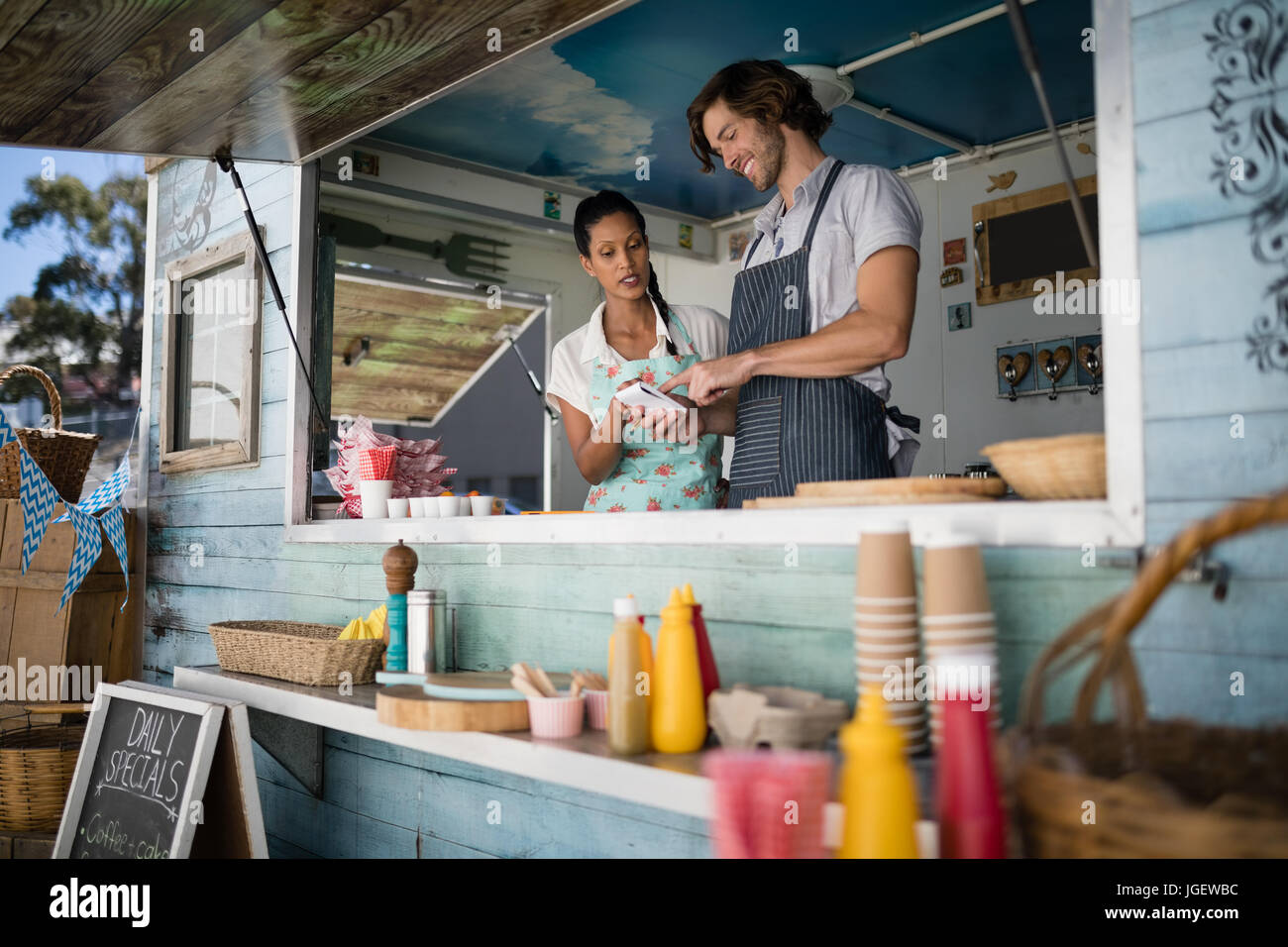 Waiter and waitress interacting with each other at counter Stock Photo ...
