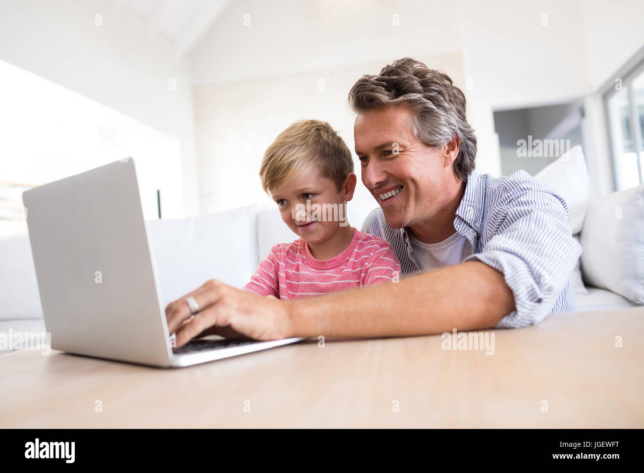 Father and son using laptop in living room at home Stock Photo - Alamy