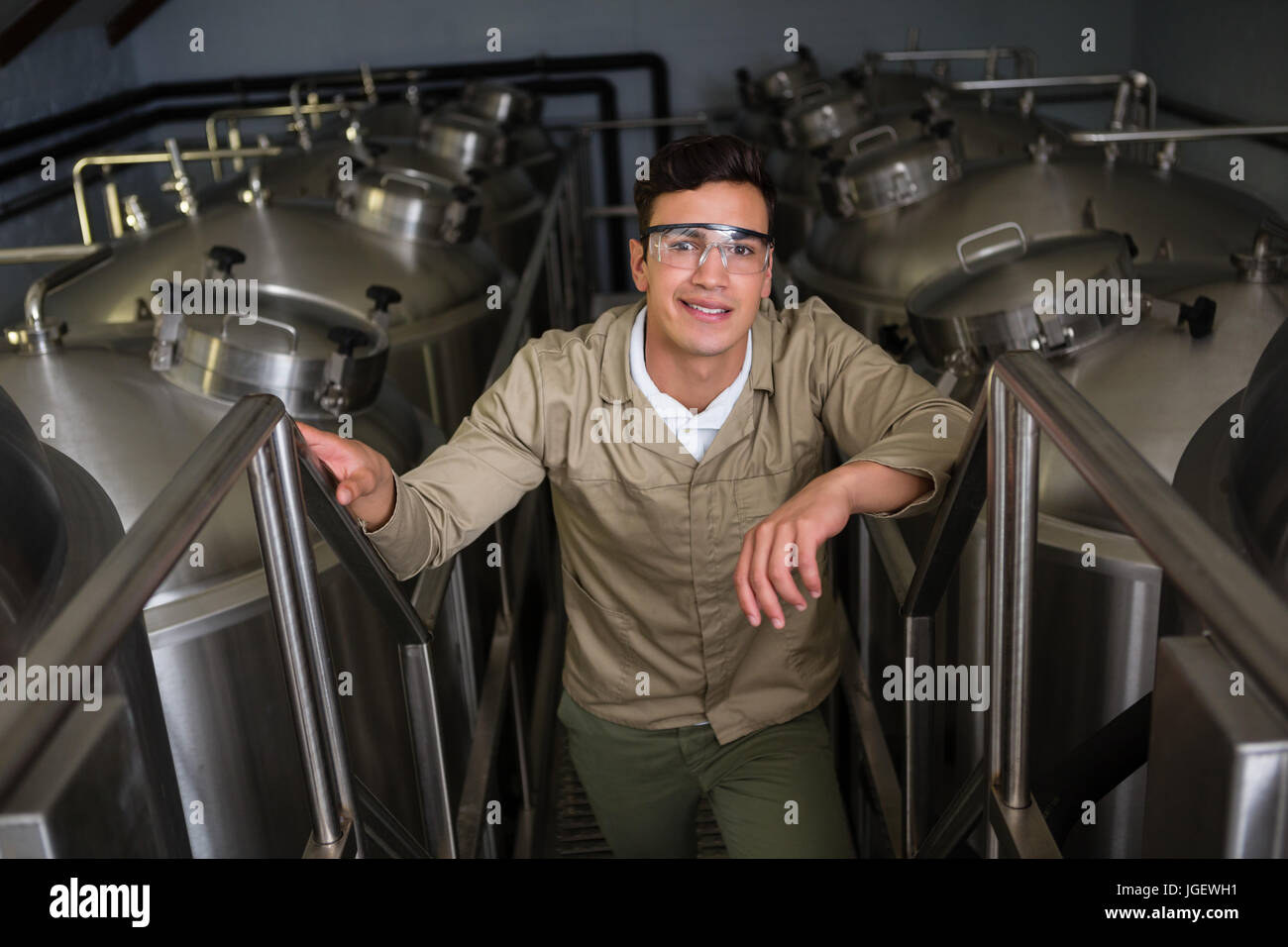 Portrait of male worker standing amidst storage tanks at warehouse ...