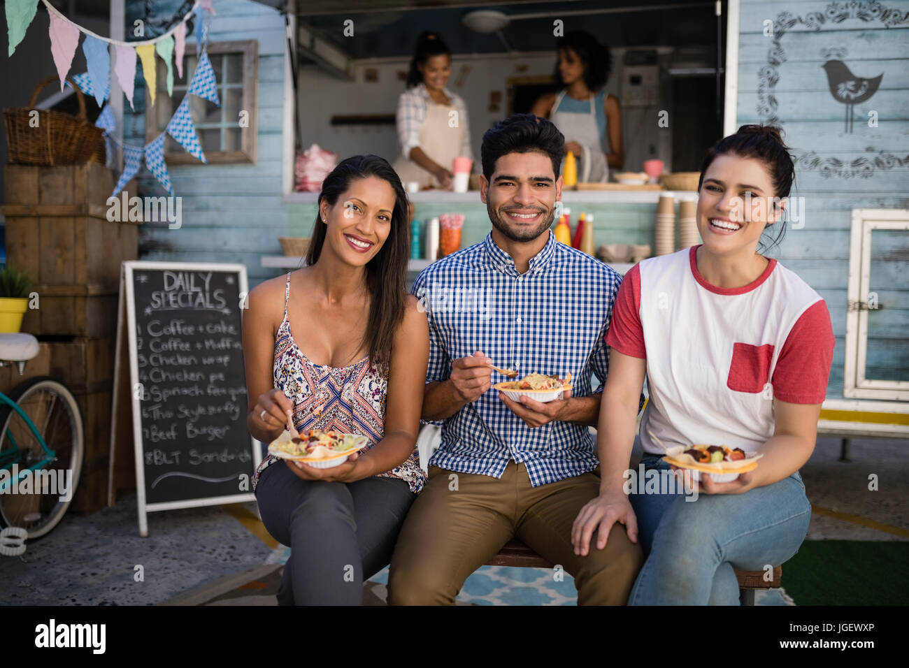 Portrait of smiling friends sitting with snacks Stock Photo - Alamy