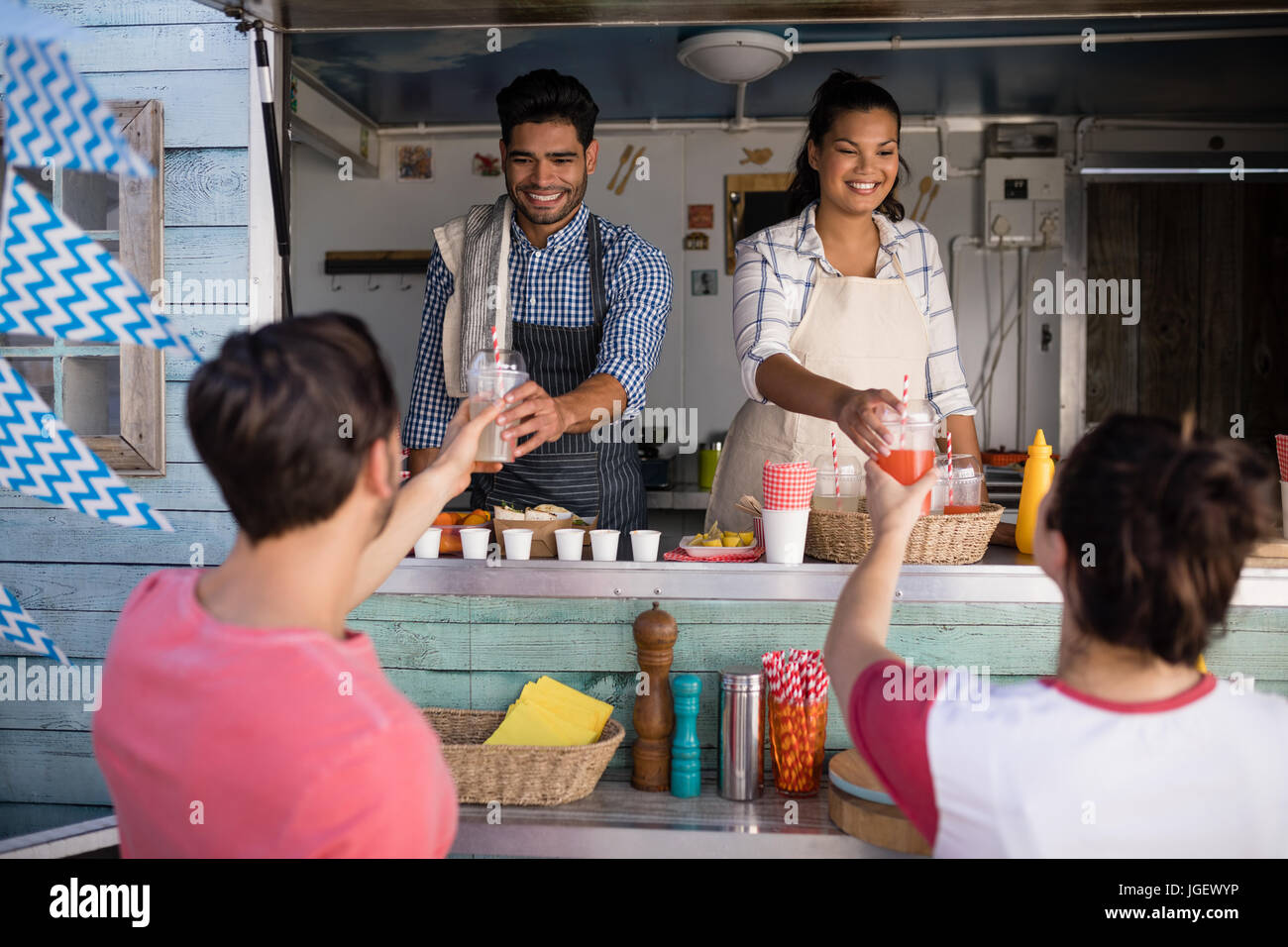 Smiling waitress and waiter giving juice to customer at counter Stock ...