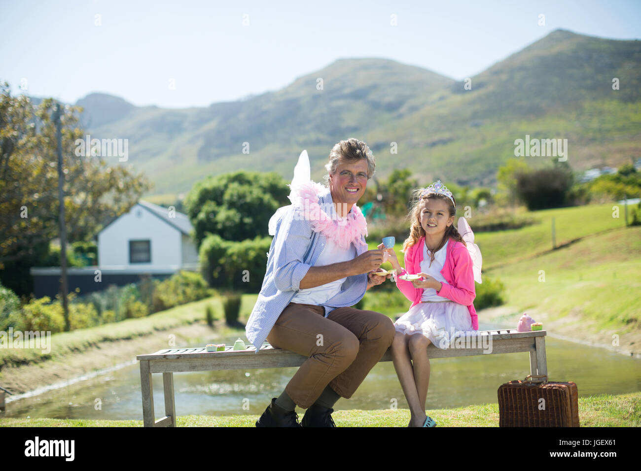 Portrait of smiling father and daughter in fairy costume having a tea ...