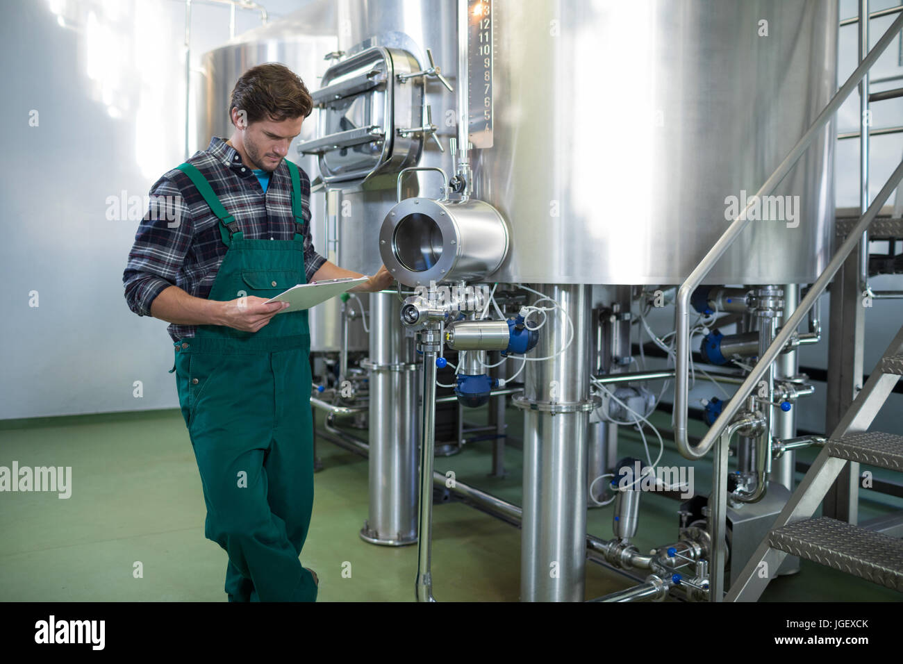 Worker reading while standing by storage tank at factory Stock Photo ...