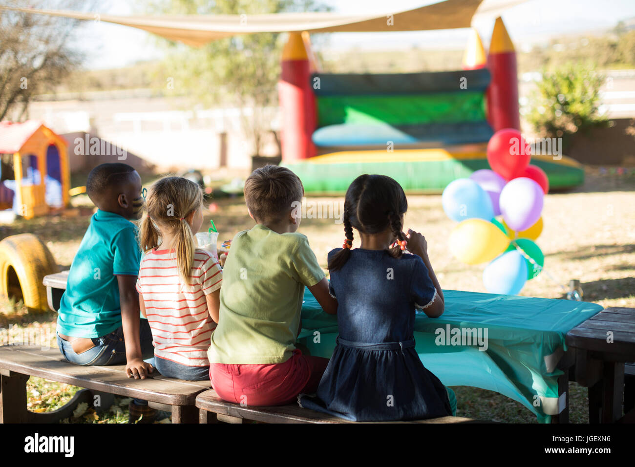 Rear view of children sitting on bench at park Stock Photo - Alamy