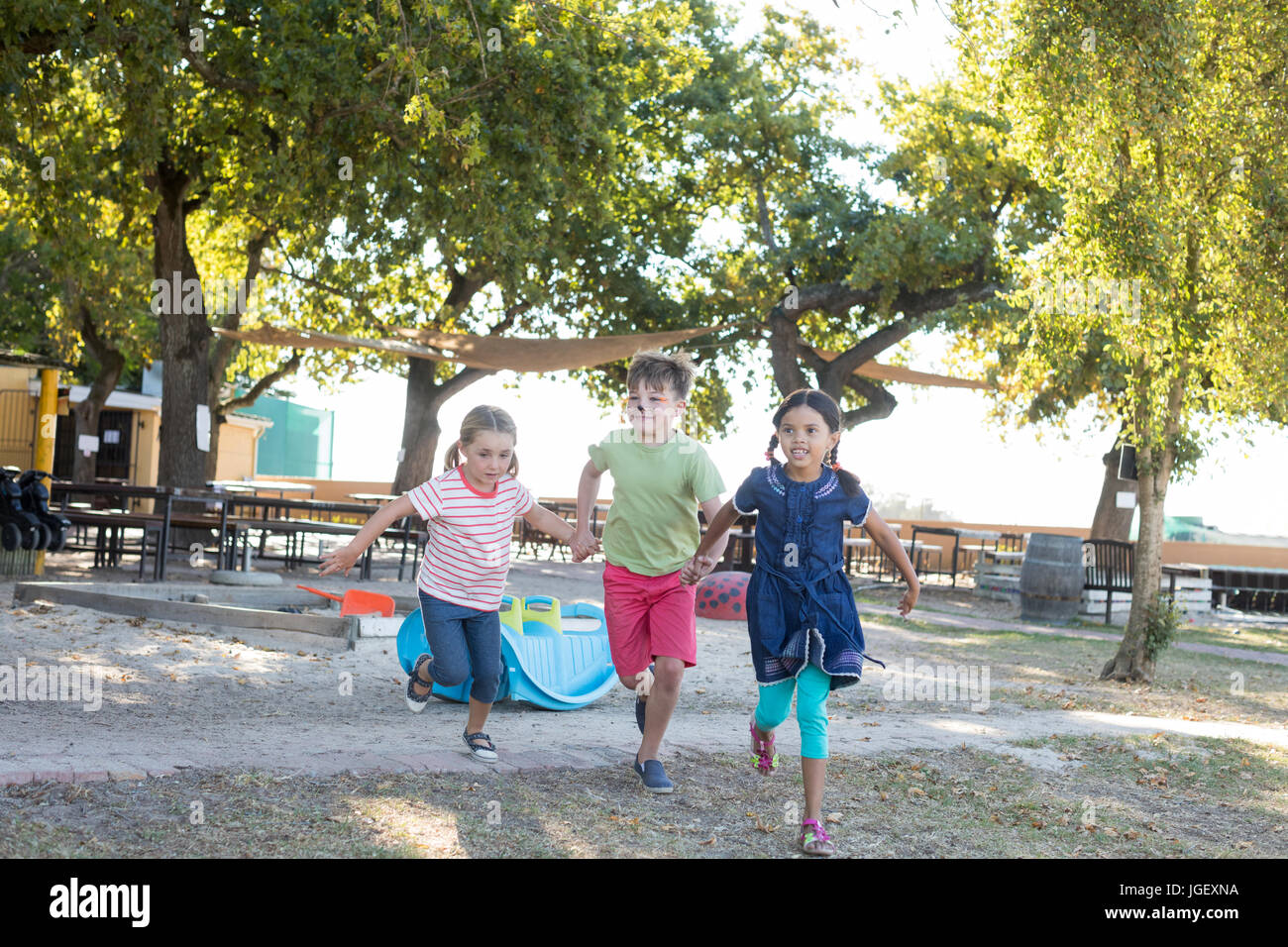 Full length of children holding hands and running on field at park ...