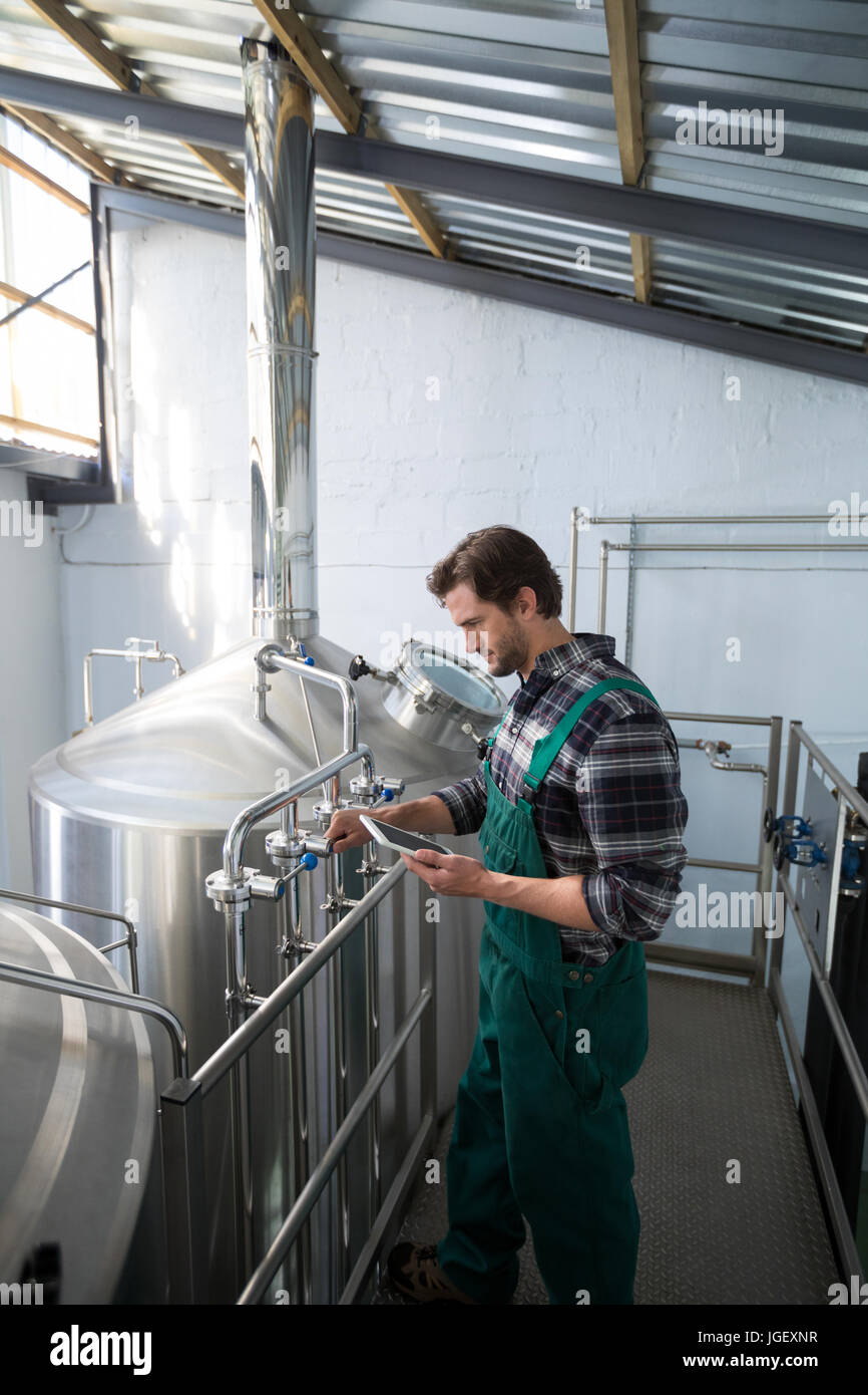 Male worker using digital tablet while examining vat at factory Stock ...