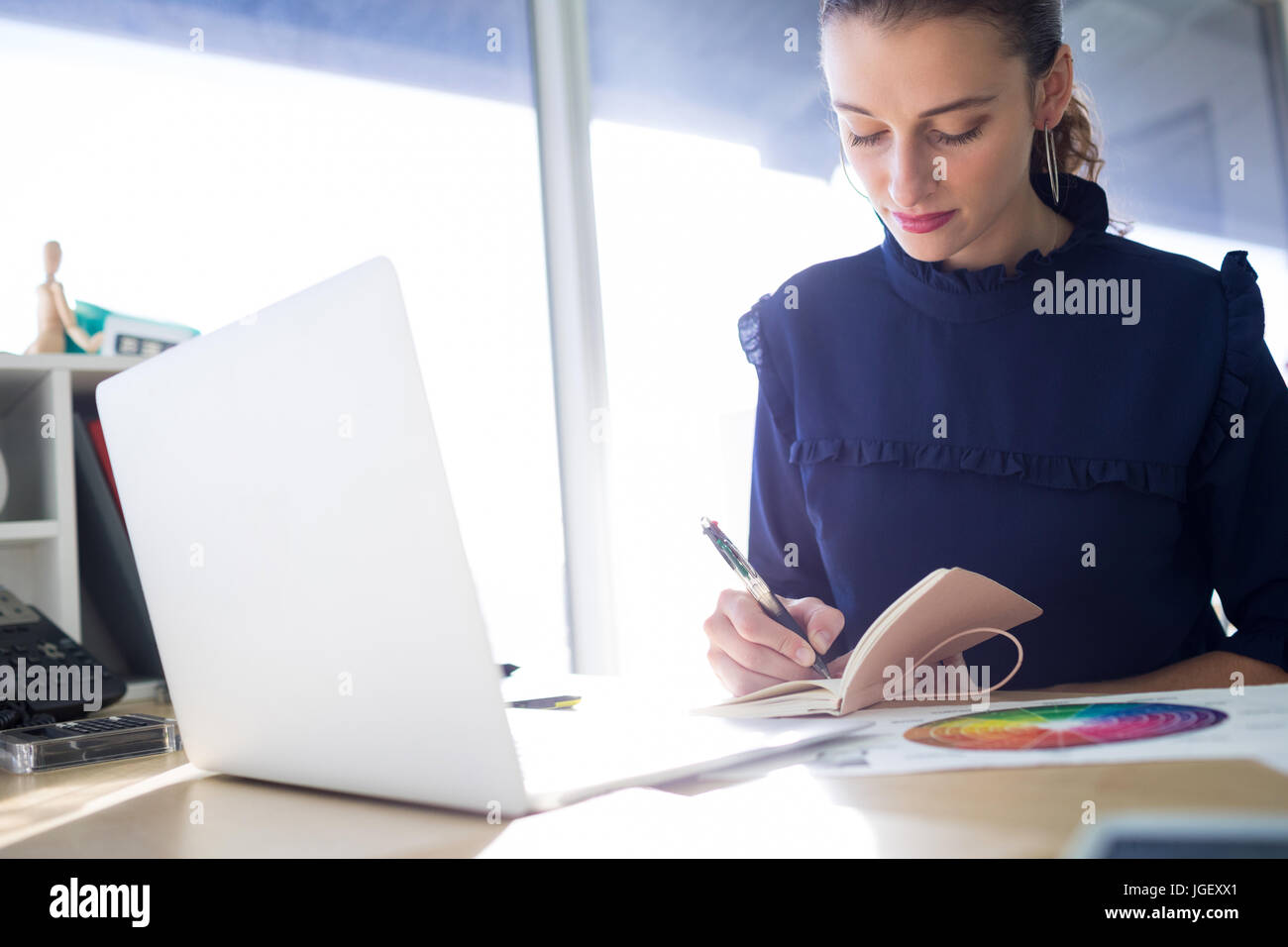 Female executive writing in diary at her desk in office Stock Photo - Alamy