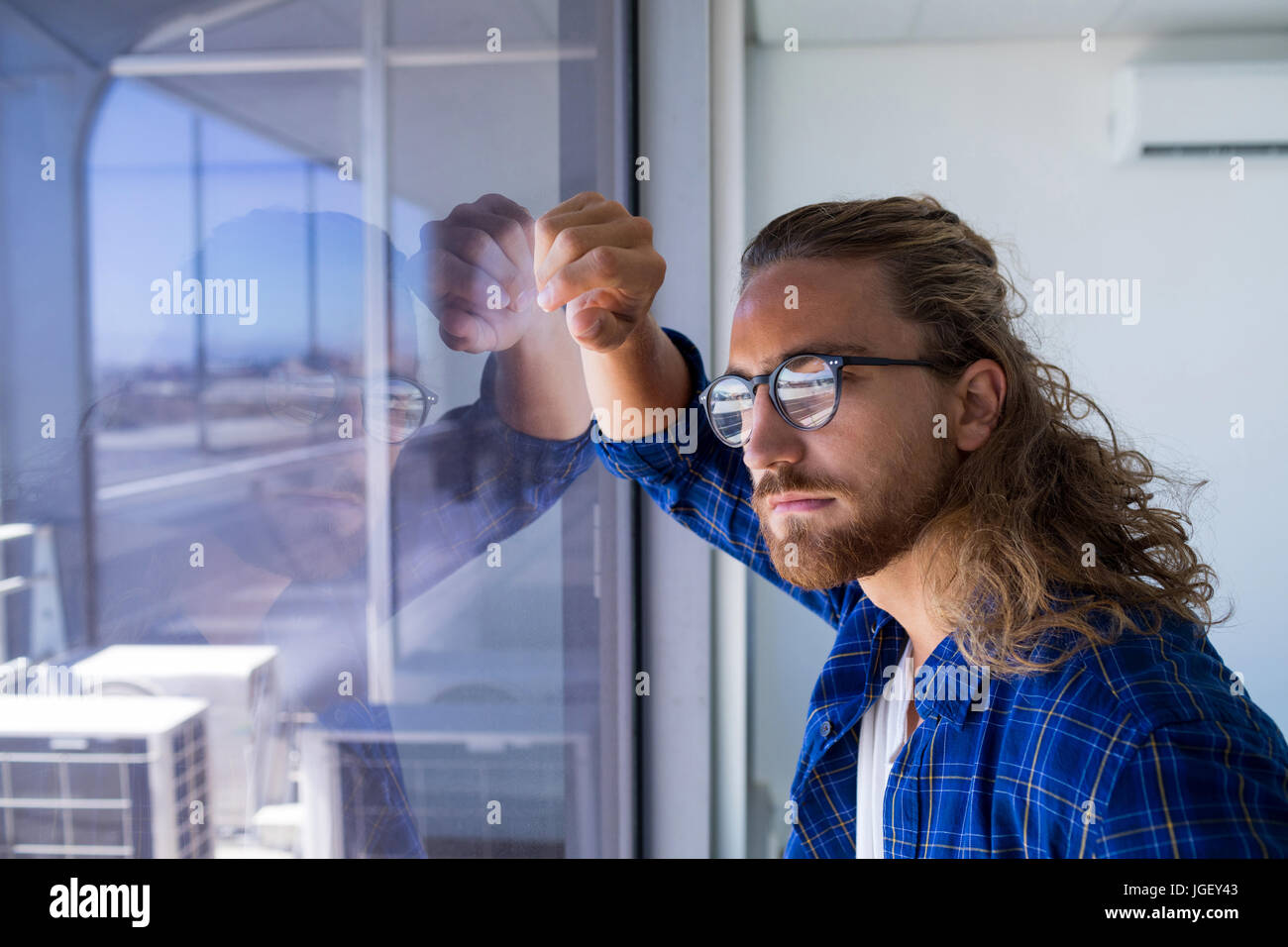 Thoughtful male executive looking through window in office Stock Photo ...