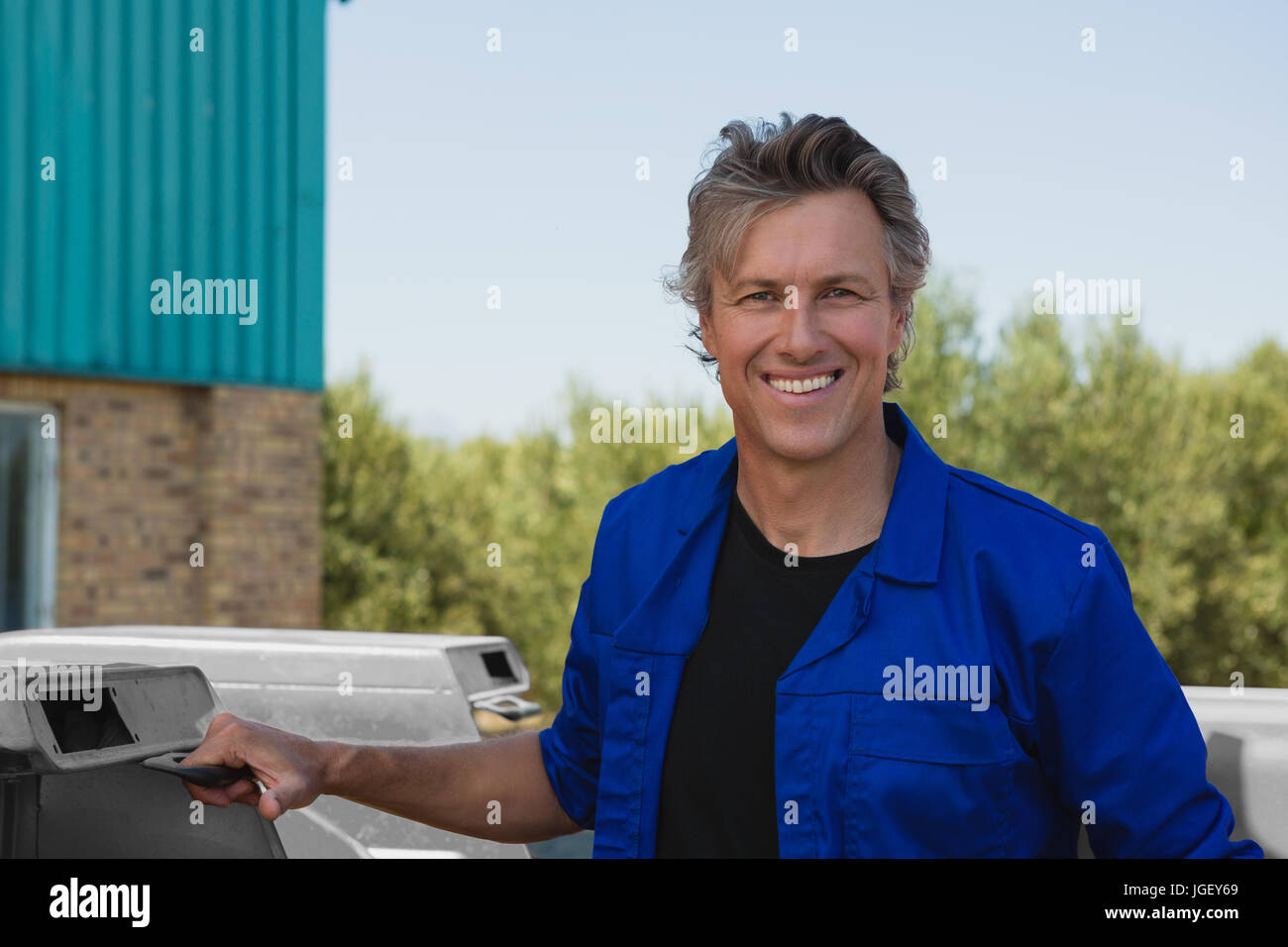 Portrait of smiling worker standing near tractor Stock Photo - Alamy