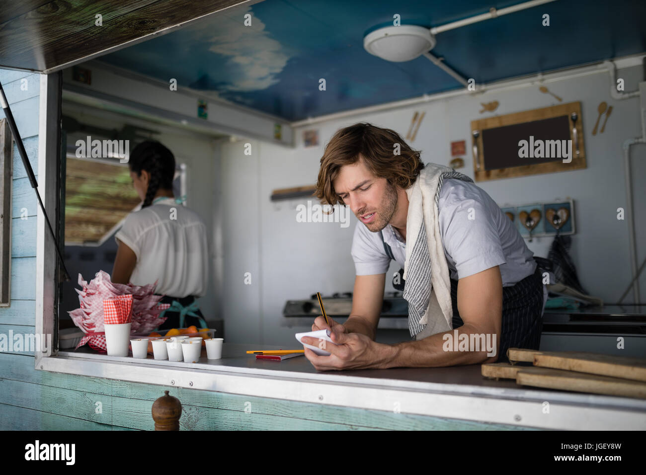 Waiter writing in notepad at counter Stock Photo - Alamy