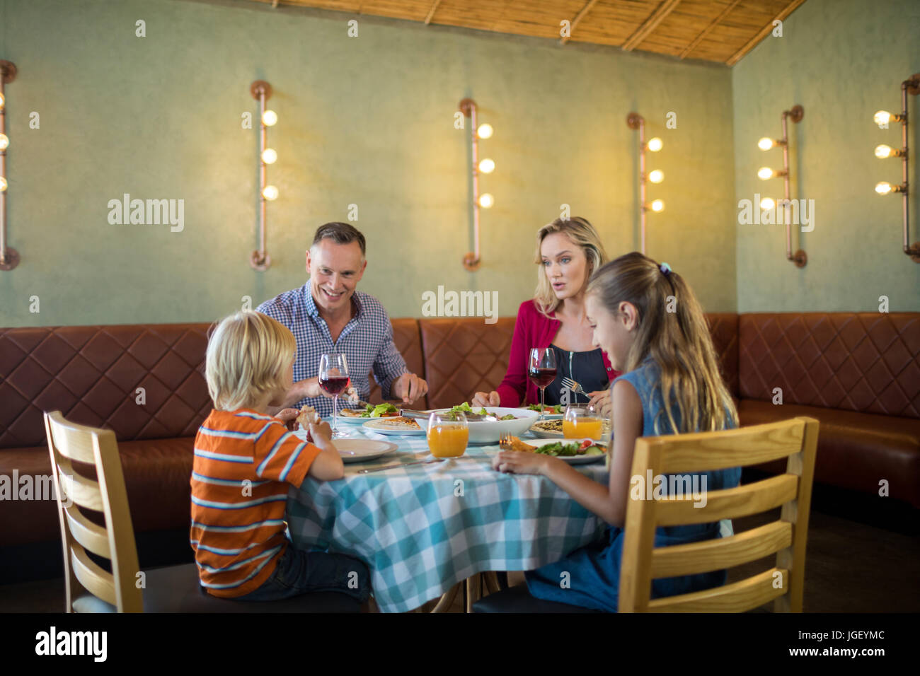 Happy family talking while dining at restauranrt Stock Photo - Alamy