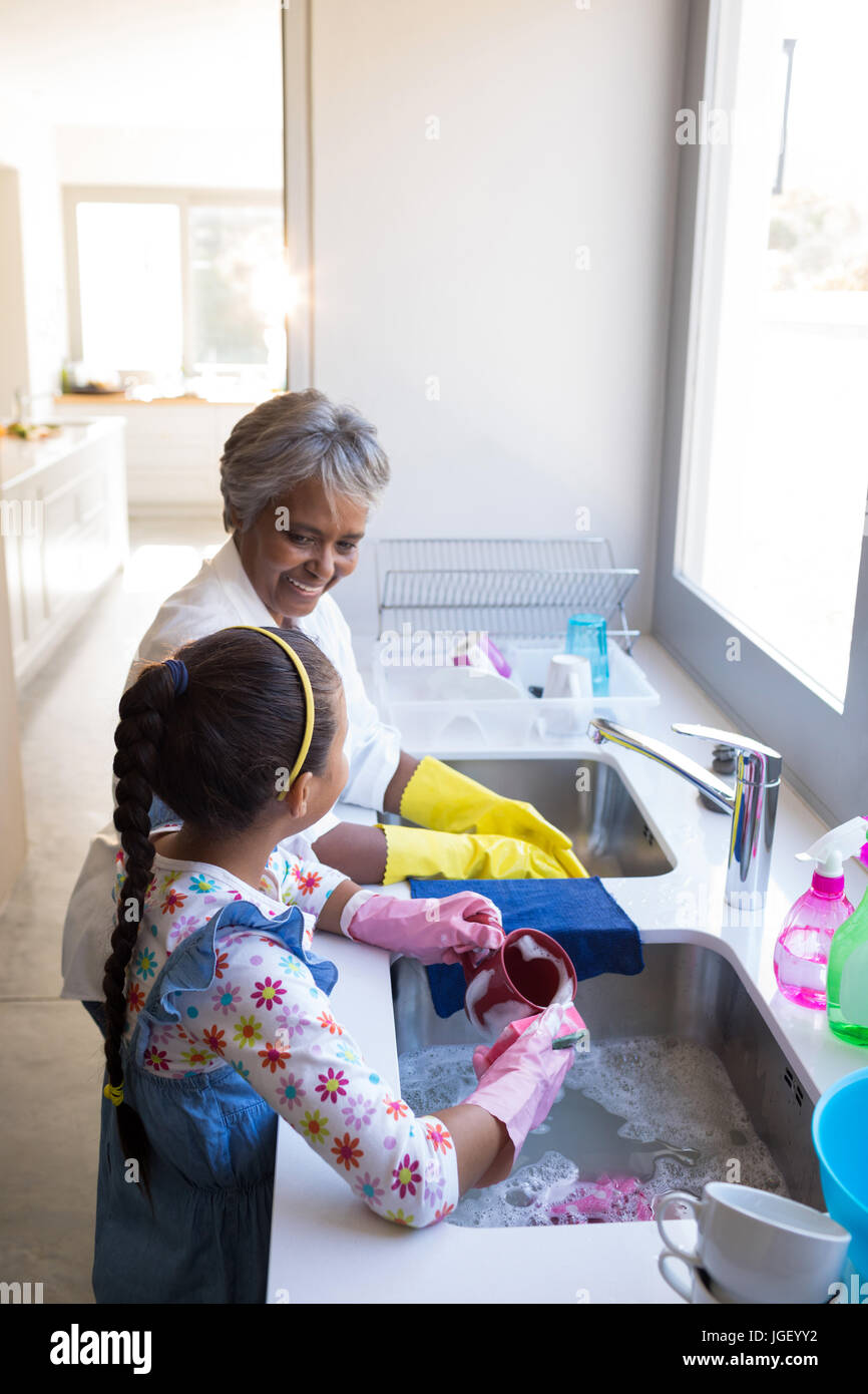 Grandmother and granddaughter washing utensil in kitchen sink at home ...
