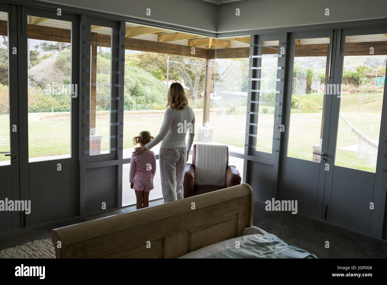 Rear view of mother and daughter standing with arms up at home Stock ...